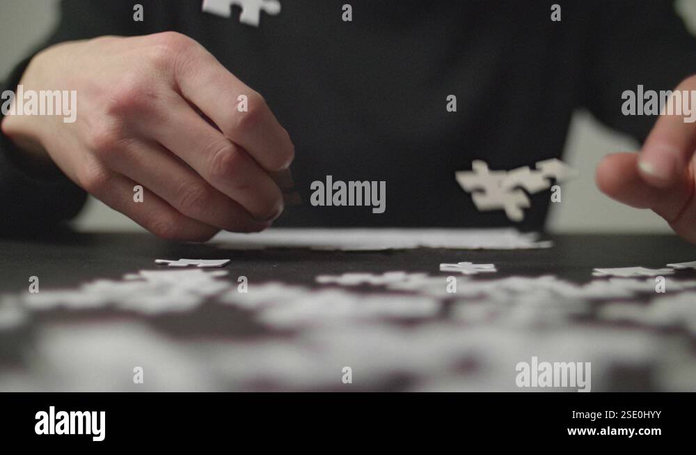 Person's hands trying to solve a puzzle in the background with white ...
