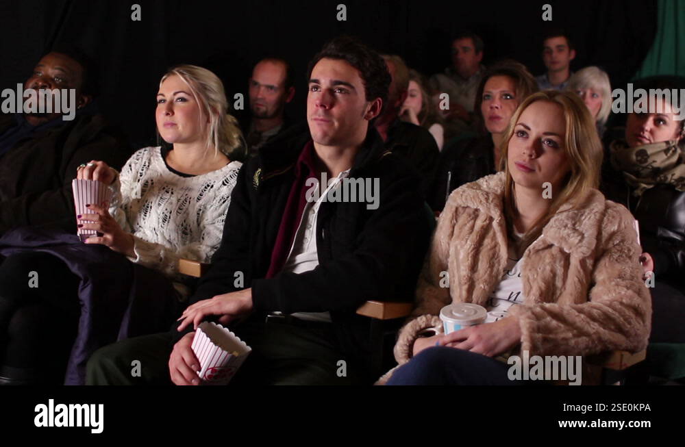 People sat in Cinema Theatre watching a film or movie whilst eating ...