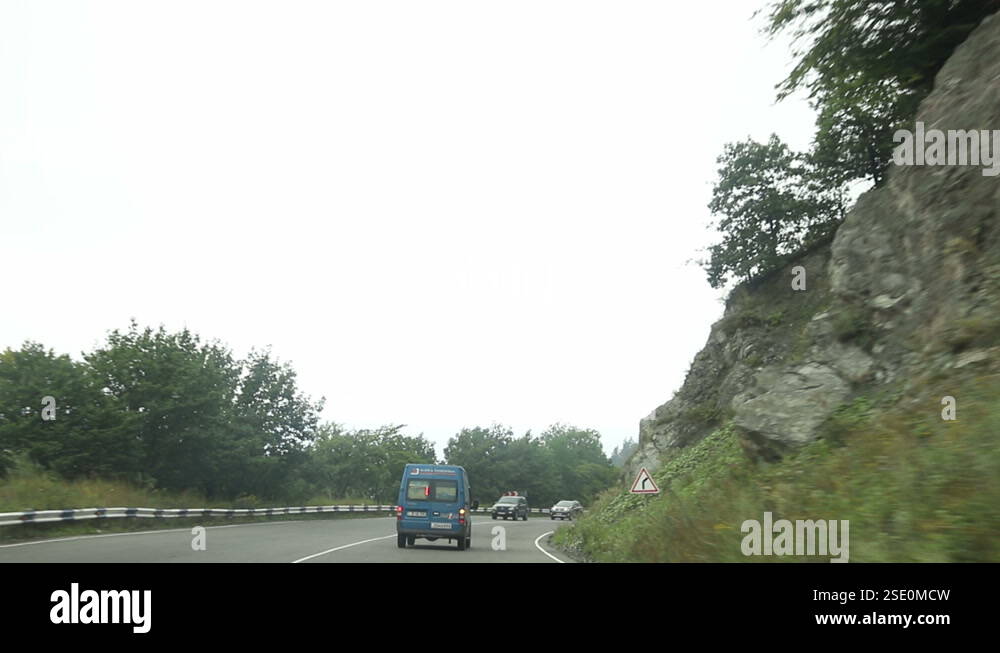 The car rides on a paved smooth road in the middle of a mountainous ...