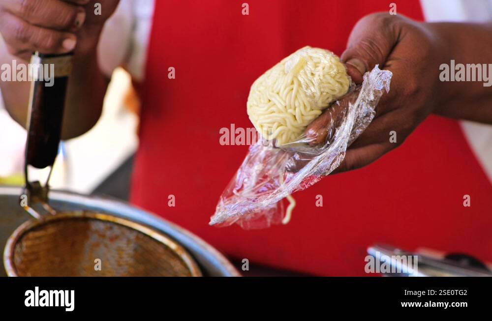 Fresh udon noodles are tossed inside a mesh strainer, ready to be ...