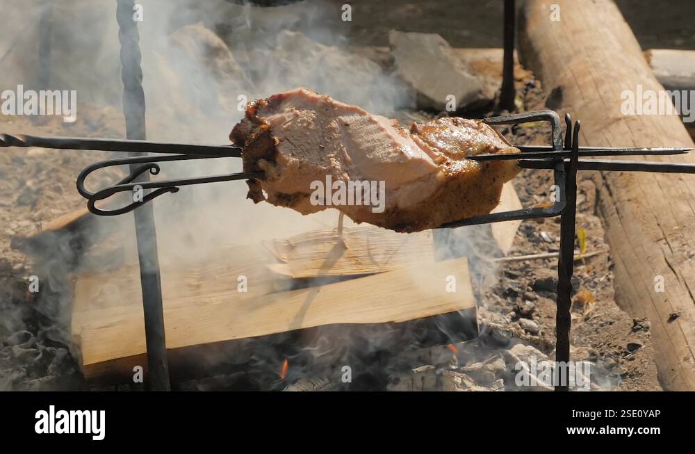 Slow motion: process of cooking large meat peaces on spit over open ...