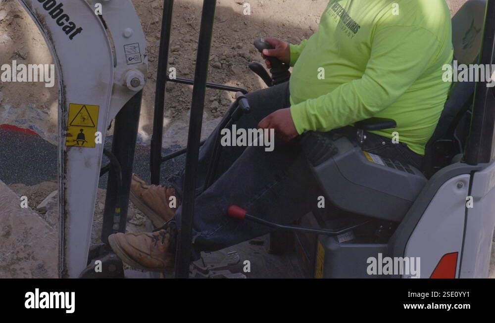 Over weight equipment operator working a mini excavator aka track hoe ...