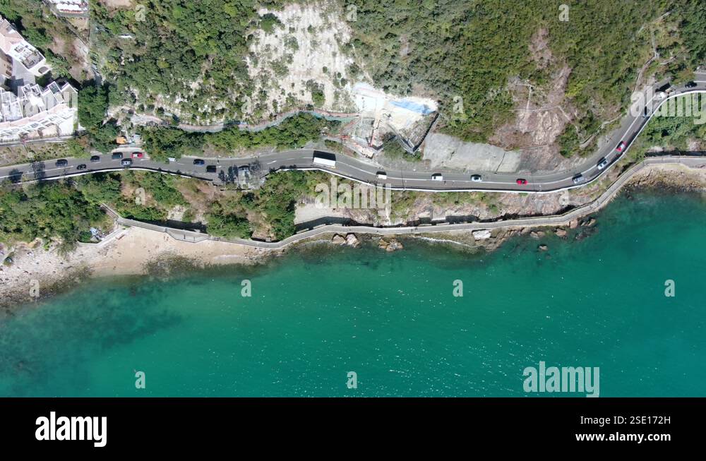 Hong Kong bay coastal road with traffic and calm turquoise water ...