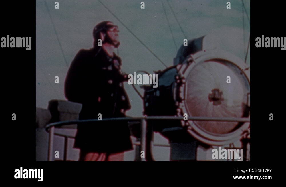 1940s: Sailor turns ship wheel. Man wears goggles, stands next to ...