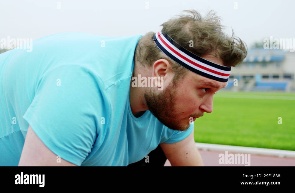 Handsome guy obese at the starting line in the stadium getting ready ...