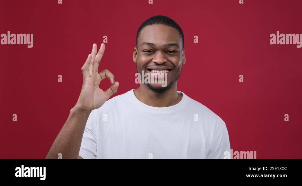 Man giving ok hand sign over maroon background Stock Video Footage - Alamy