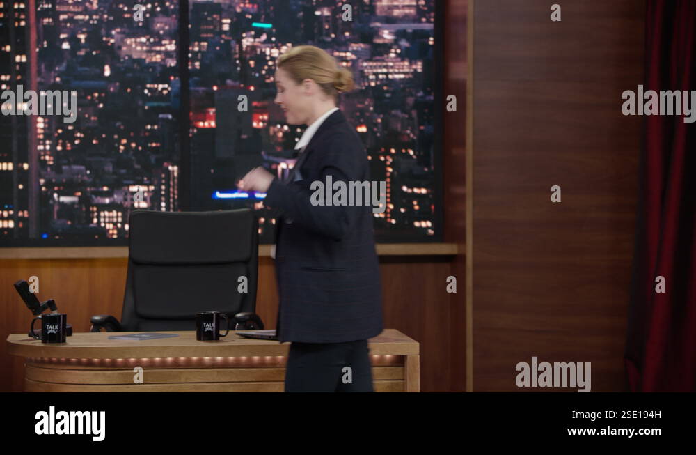 Late-night talk show female host performing her monologue, looking into ...