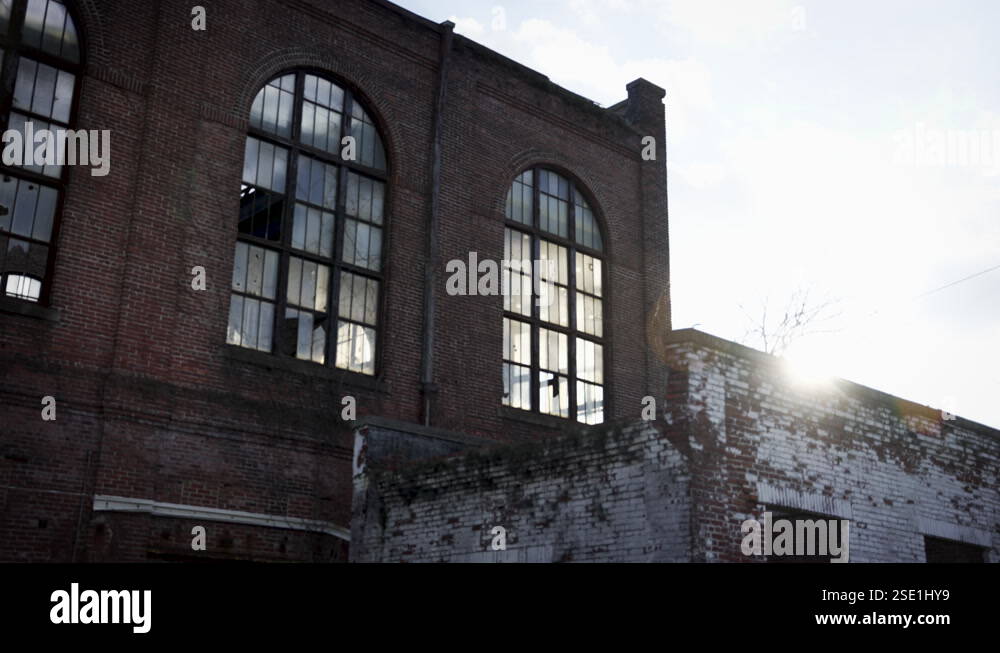 Pan and sun flare across the large windows of an old, abandoned ...