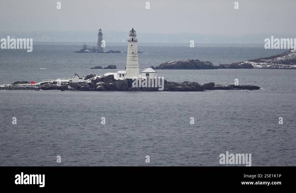 Waves lick the rock base of Boston Light as it flashes intermittently ...