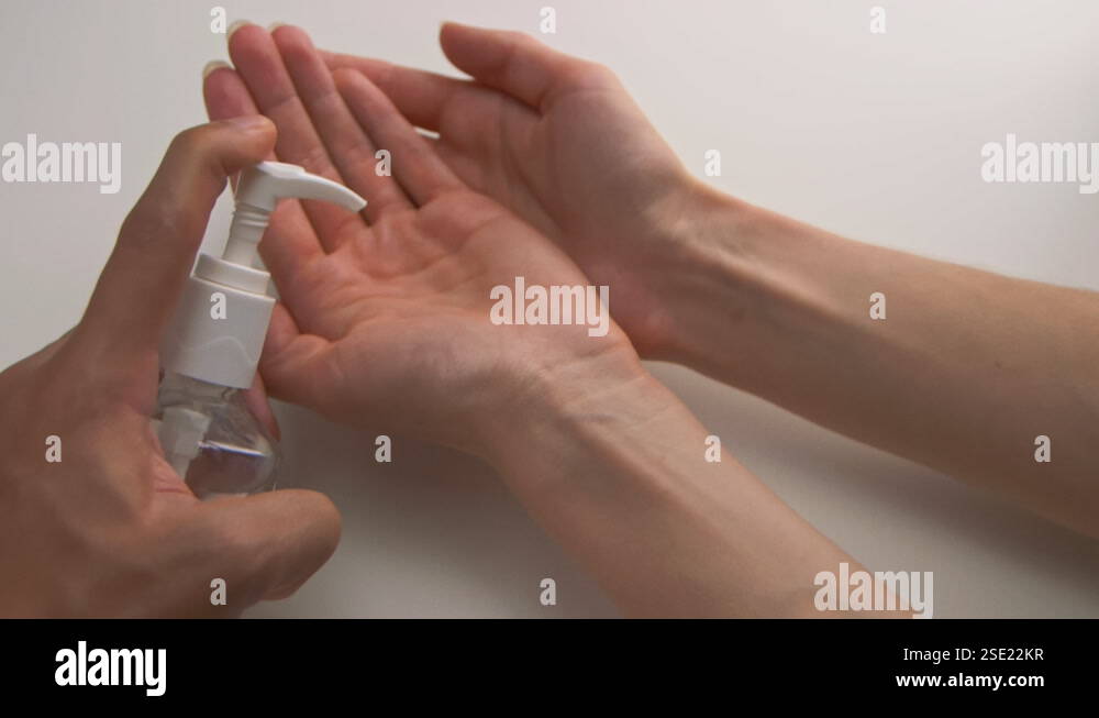 A man's hand pumps hand sanitizer into a female's hands and she rubs ...