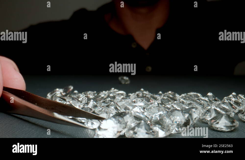 CLOSE UP: The Jeweler pours diamonds on the work table and examine them ...