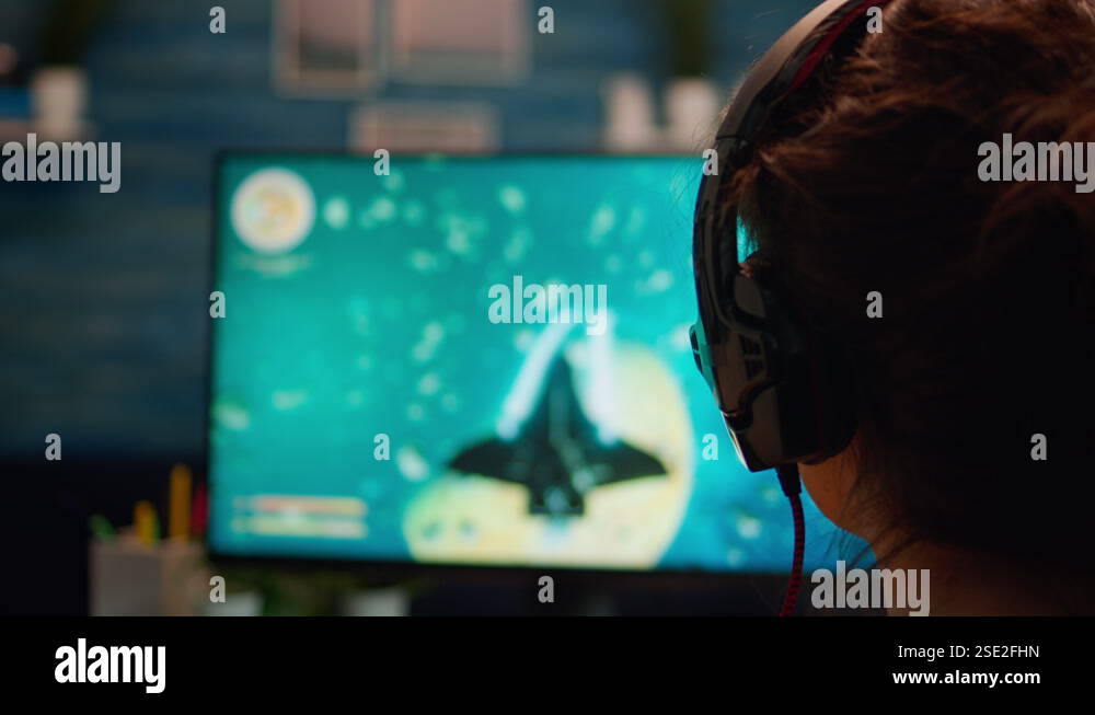 Over the shoulder pro gamer woman playing computer FPS shooter video ...