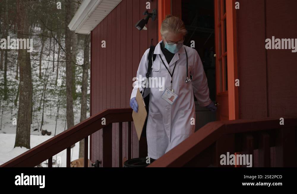 Woman doctor nurse comes out of home visit and walks in the winter snow ...