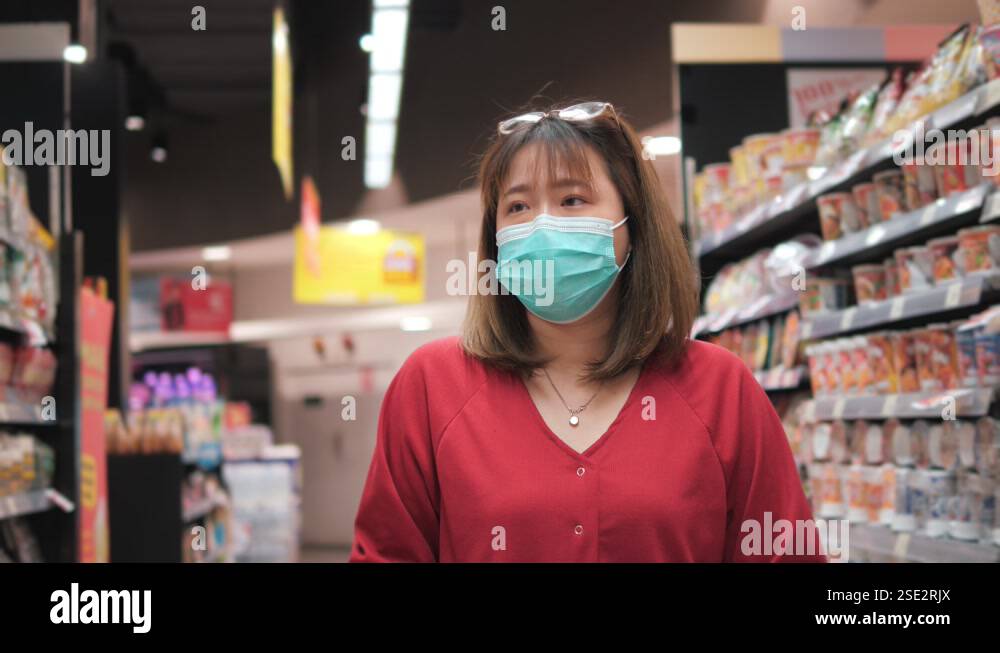 Asian woman wearing face mask push shopping cart in supermarket ...
