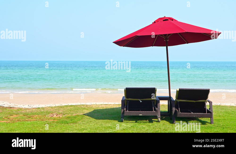 Two empty sun loungers sit under a shade umbrella facing the incoming ...