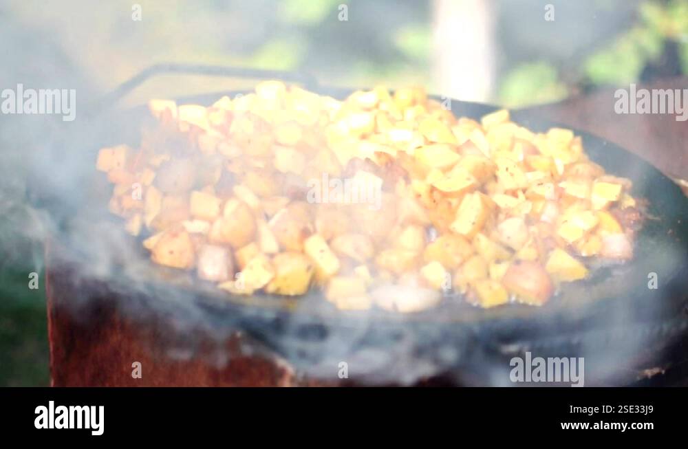 Cooking fried potatoes with lard over the fire. Fried vegetables on a ...