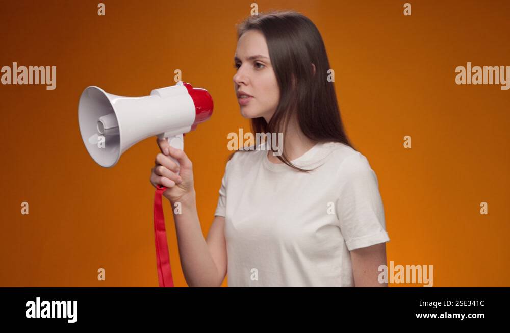 Young woman announcing something using loudspeaker against yellow ...