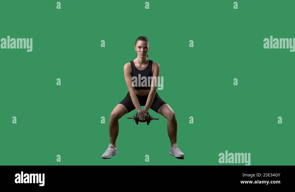 Fit woman doing squat pulse exercise with dumbbell. Full body on green ...