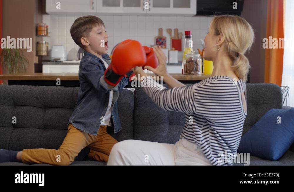 Little boy having fun wearing boxing gloves with her loving mother ...