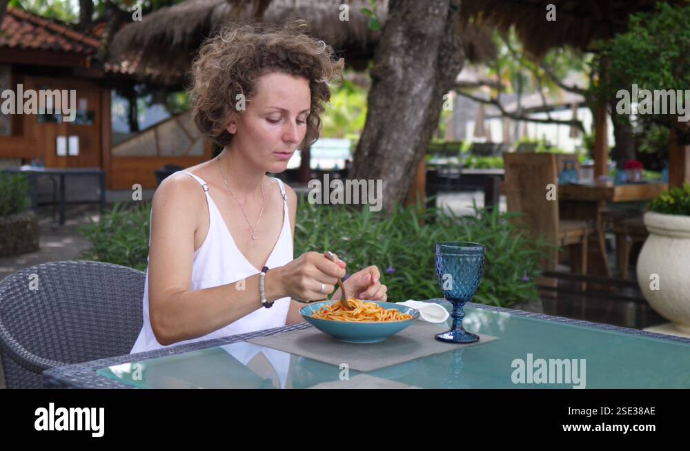 Caucasian woman takes off her face mask to eat pasta in outdoor ...