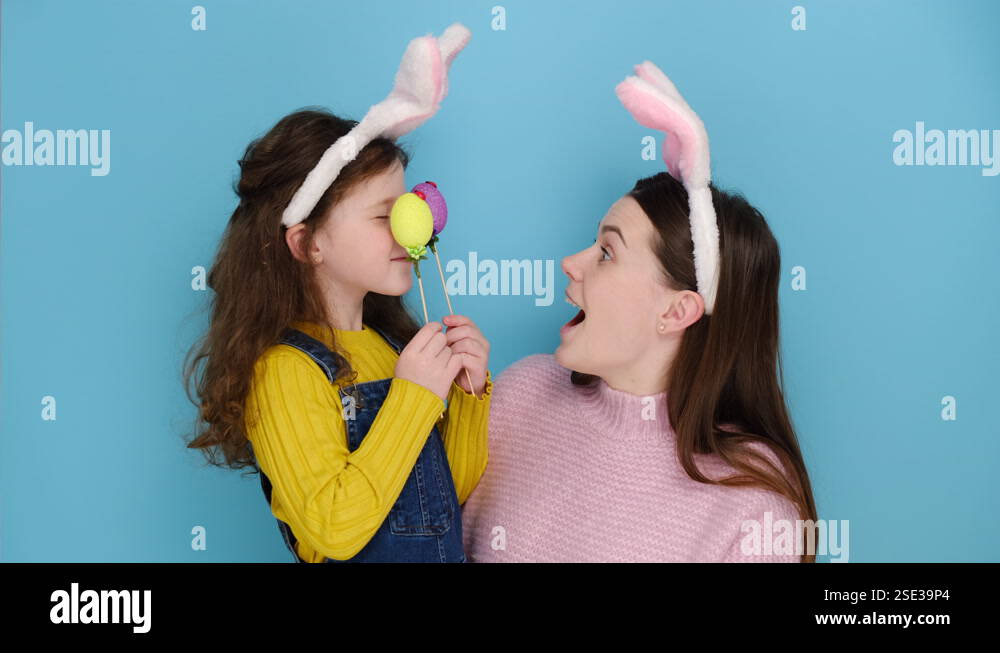Emotional mother with pink bunny ears carries little girl who holds ...