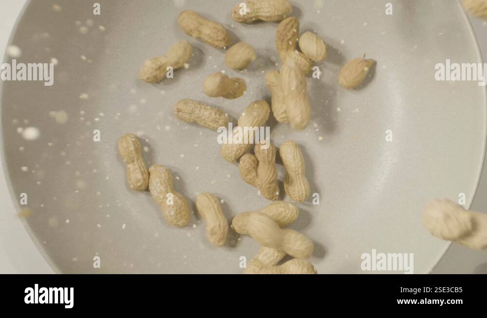 Overhead View of Unshelled Peanuts Falling into White Bowl and Filling ...