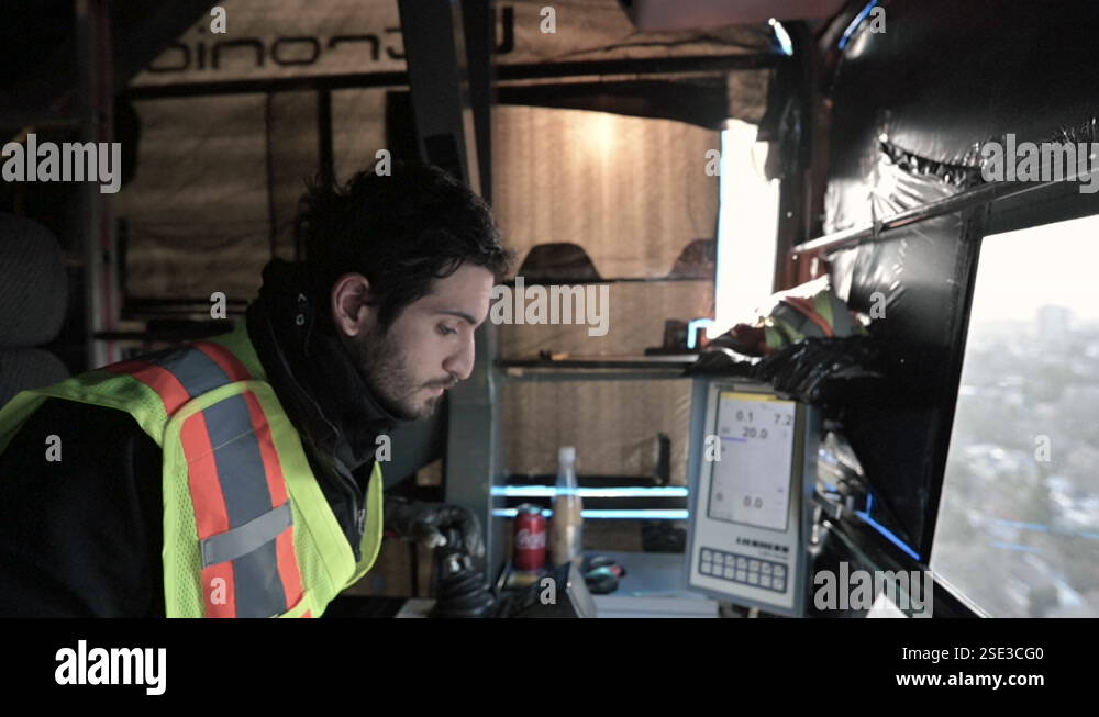Crane Operator operating tower crane in winter as snow flys through the ...