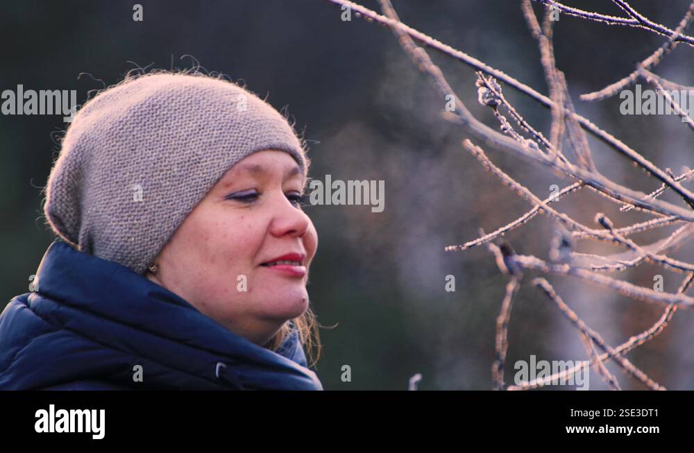 Close-up of a young woman's face with a smile, steam coming out of her ...