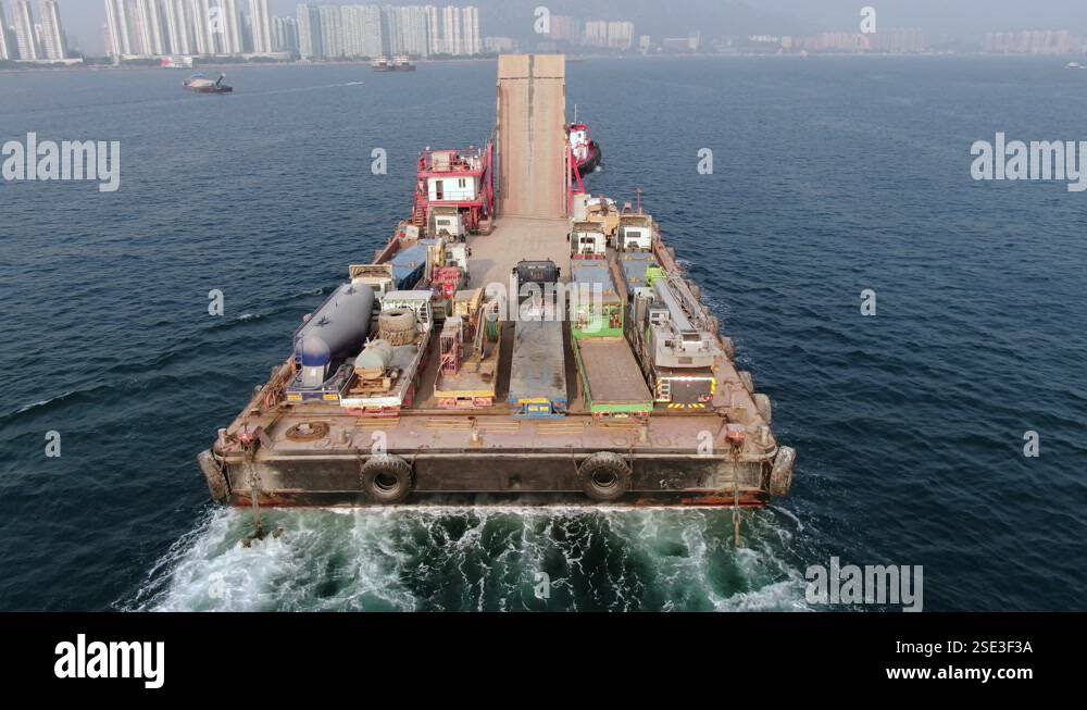 Barge loaded with Concrete mixer trucks pulled to port by a Tugboat in Stock Video Footage - Alamy