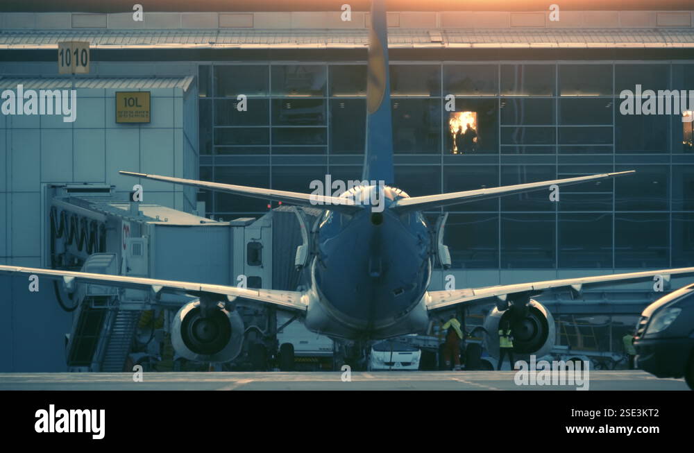 Airplane stand at the airport terminal. Airport staff servicing the ...