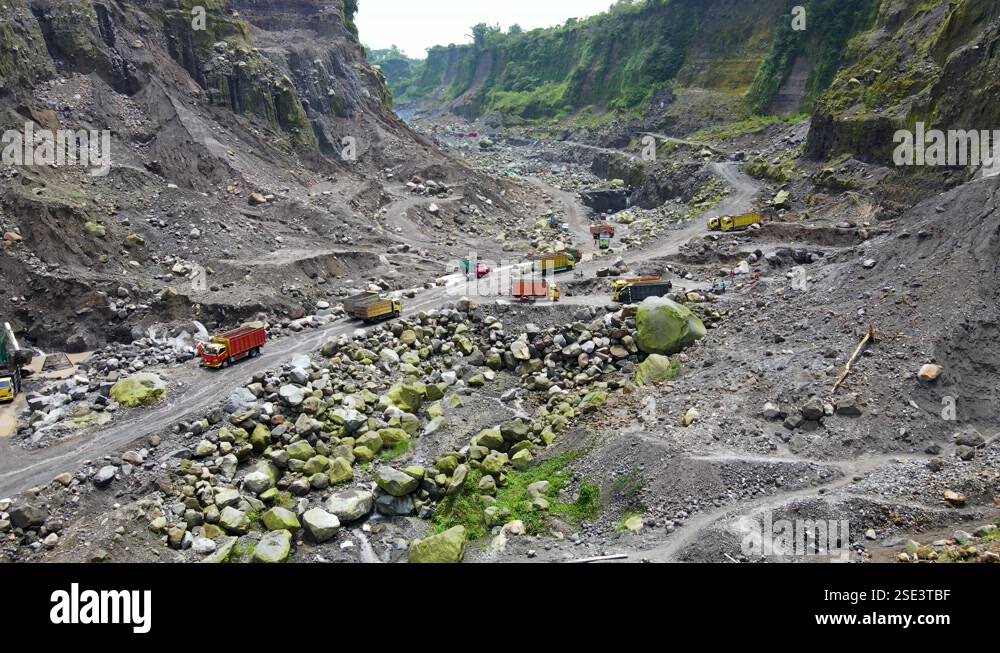 Dump trucks transport output in open pit mine near Magelang, Indonesia ...