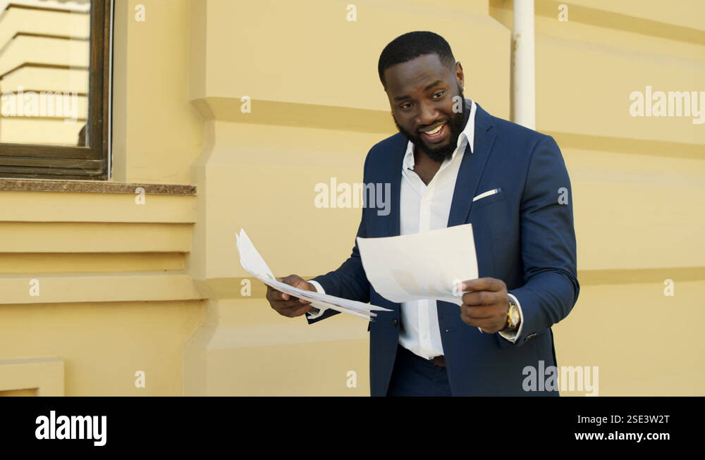 African businessman reading papers outside. Afro man checking documents ...