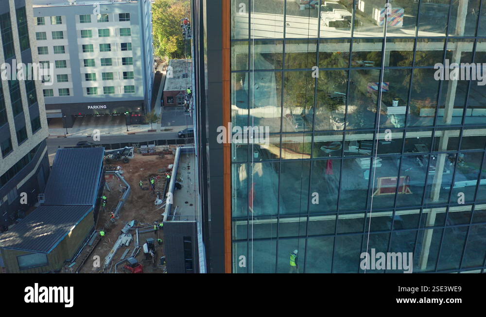 Construction workers at a bustling multi-story job site. Descending ...