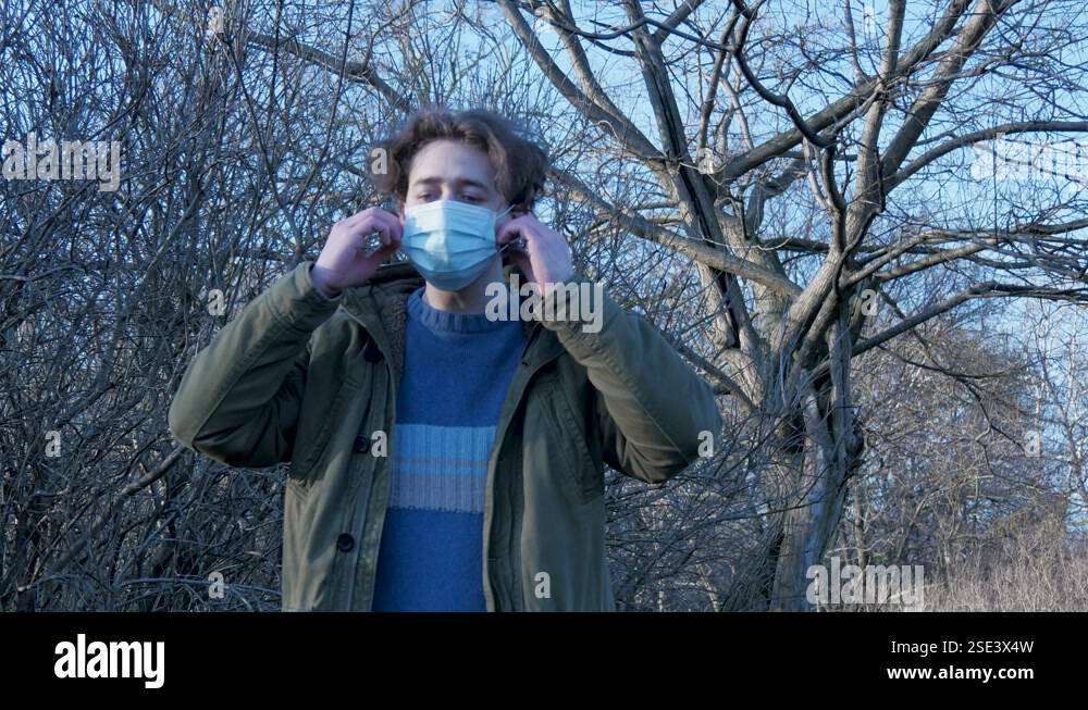 Young man tired of coronavirus pandemic. He tears disposable face mask ...