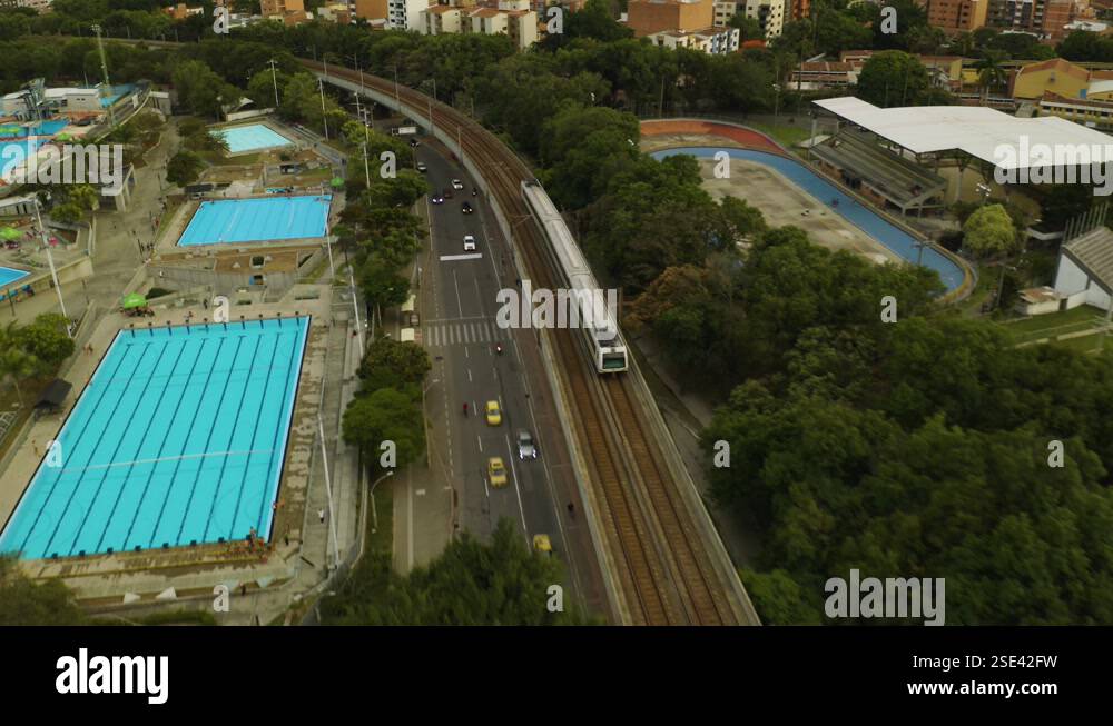 Aerial Tracking Shot of Subway Train Passing Swimming Pools in Medellin ...