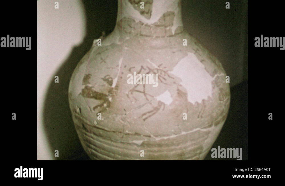 1960s: Figurine in museum. Vase. Cuneiform on stone. Person walks ...