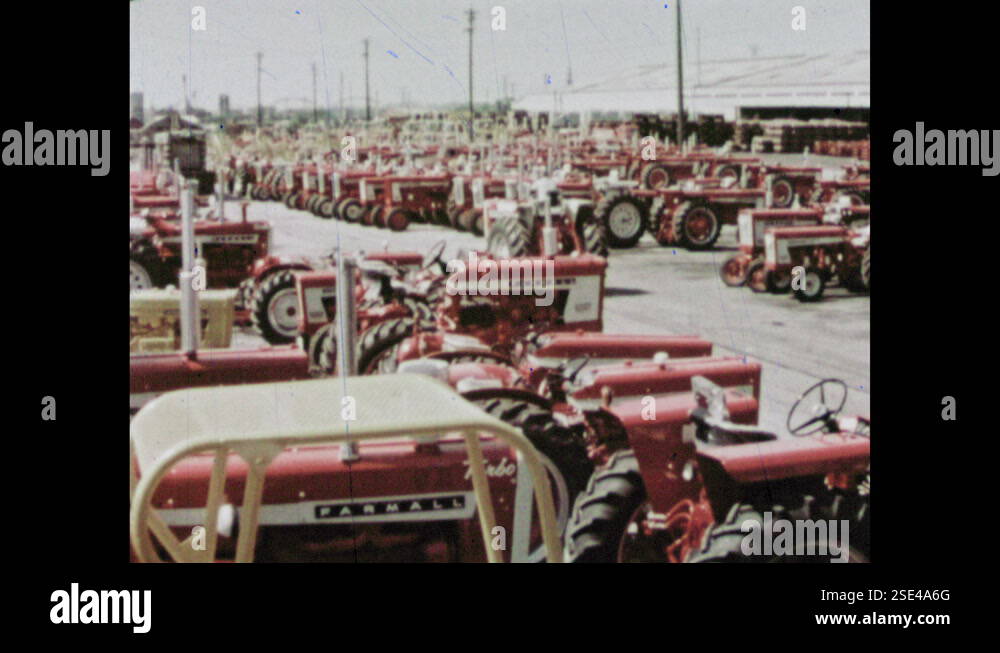 1960s: Person drives tractor through tractor lot. Construction material ...