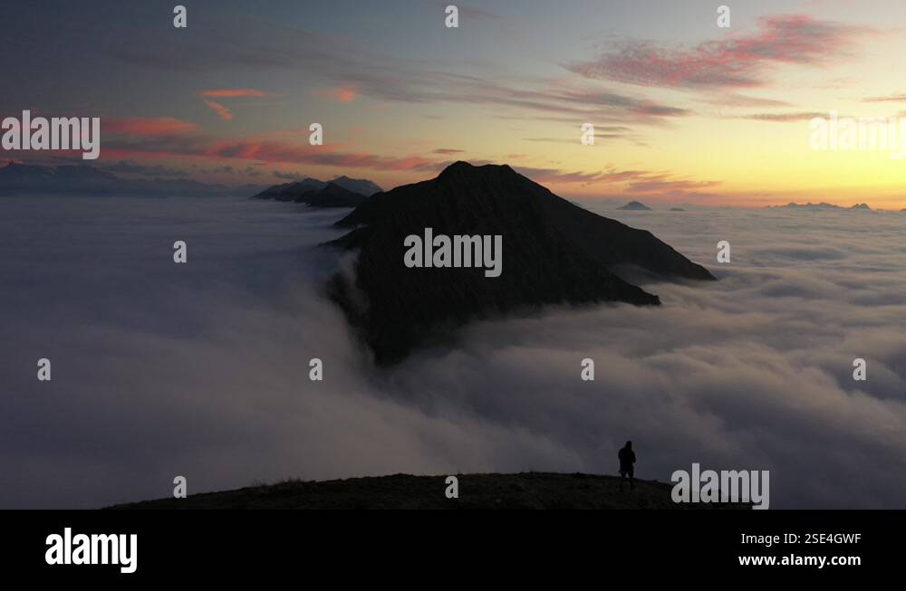 A man walks by himself on the edge of a mountain at extreme altitude ...
