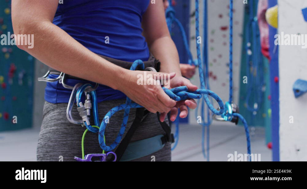 Midsection of caucasian woman knotting rope in a harness belt at indoor ...