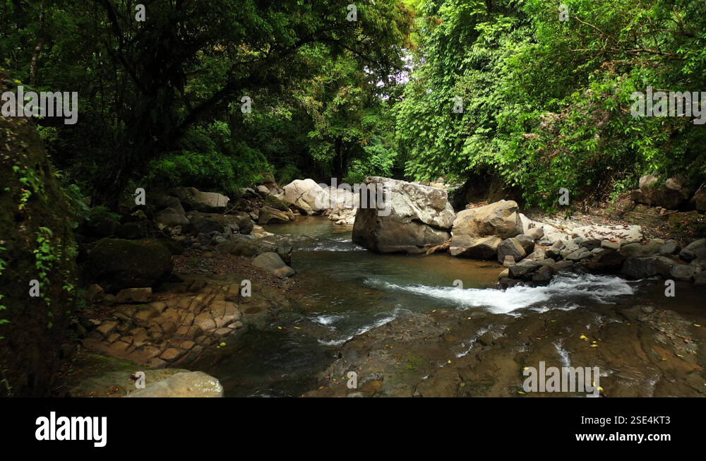 flying over a river with giant rocks in a tropical forest Costa Rica ...