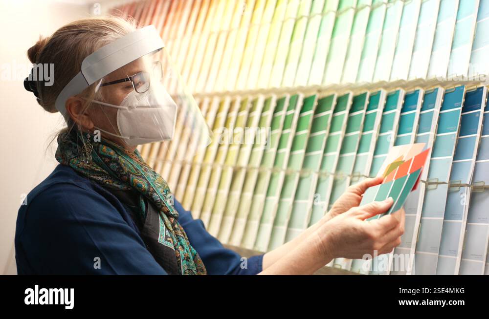 Woman wearing ppe face shield and mask shopping for paint in a hardware ...