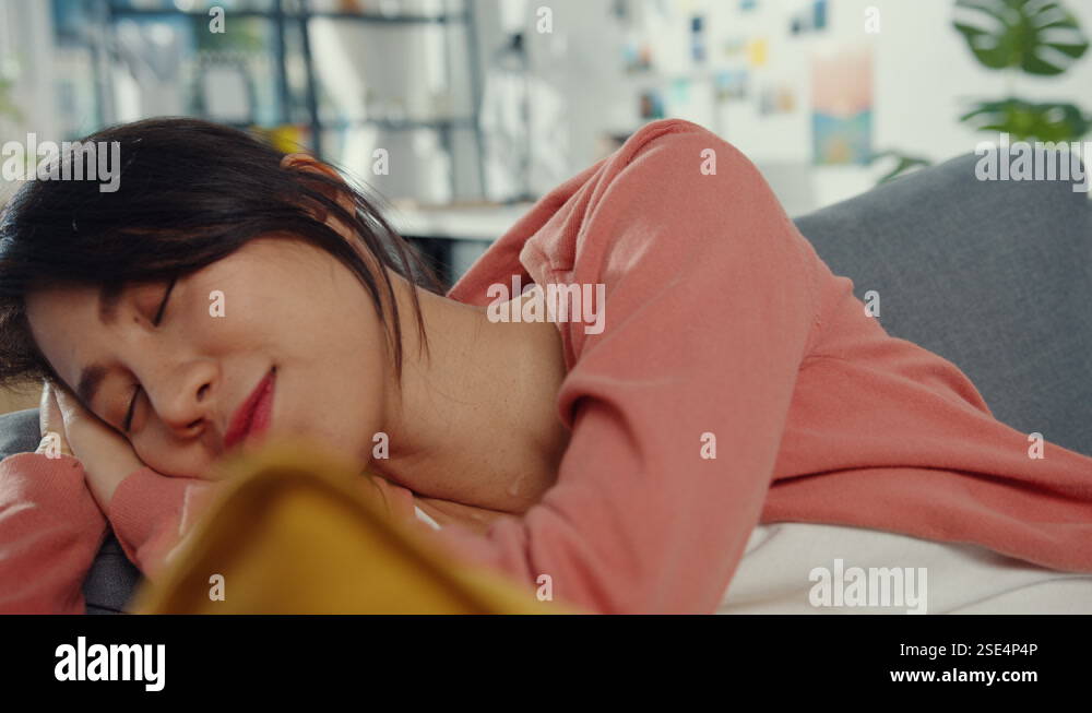 Beautiful Asia lady feel relax lay down on sofa with pillow at living ...