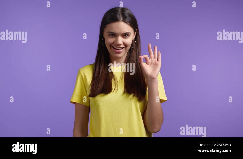Woman showing Ok sign over violet studio background. Positive young ...