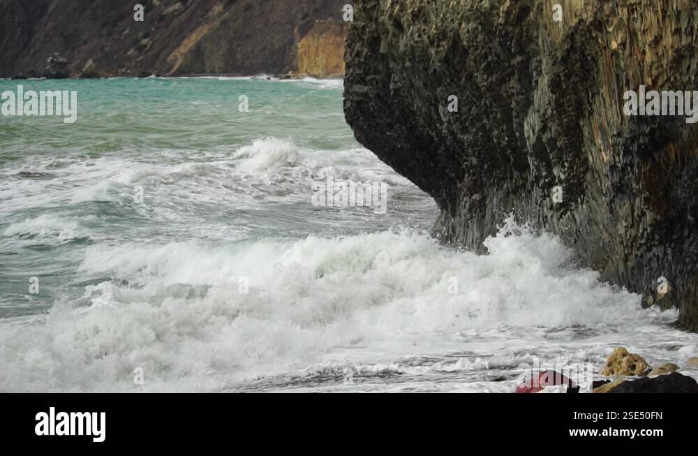 Stormy sea on sunset. The waves crash into the volcanic basalt rock ...