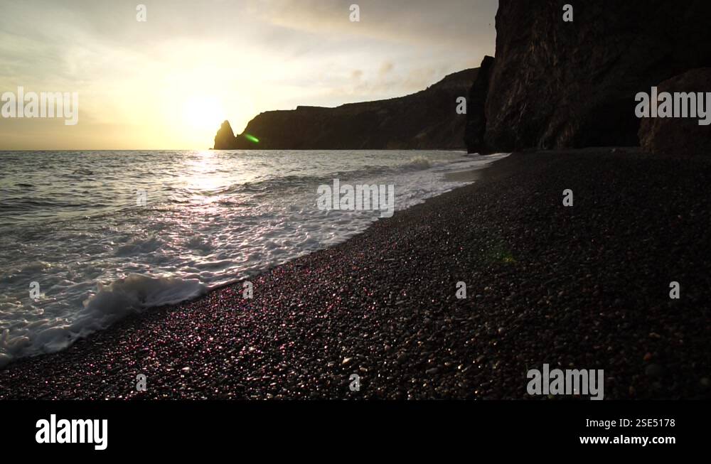Stormy sea on sunset. The waves crash into the volcanic basalt rock, lit by the Stock Video ...