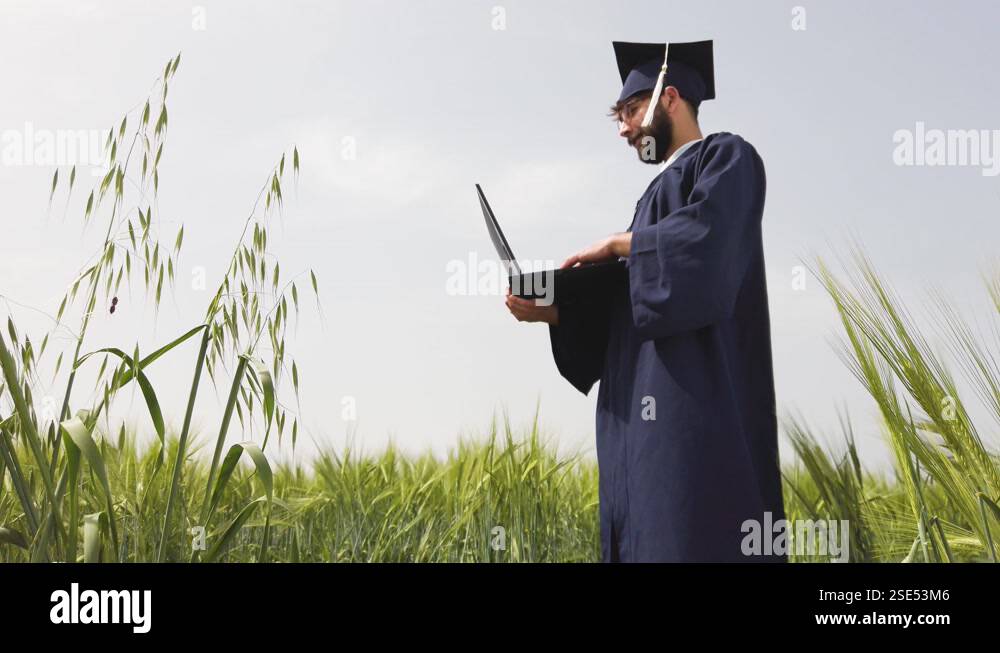 Graduation man alone in nature, looking at laptop, throwing the blue ...