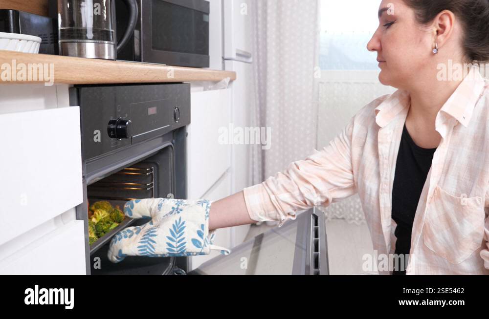 Woman take out crispy chicken on a baking sheet from the oven Stock ...
