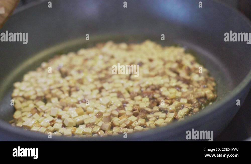 Smoked tofu slices frying in a pan with oil sizzling. Vegan delicious ...