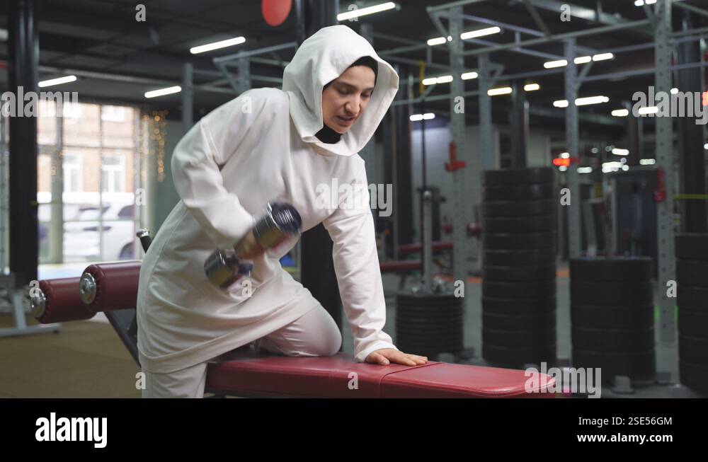 muslim woman in hijab for sports exercises with dumbbells in the gym ...