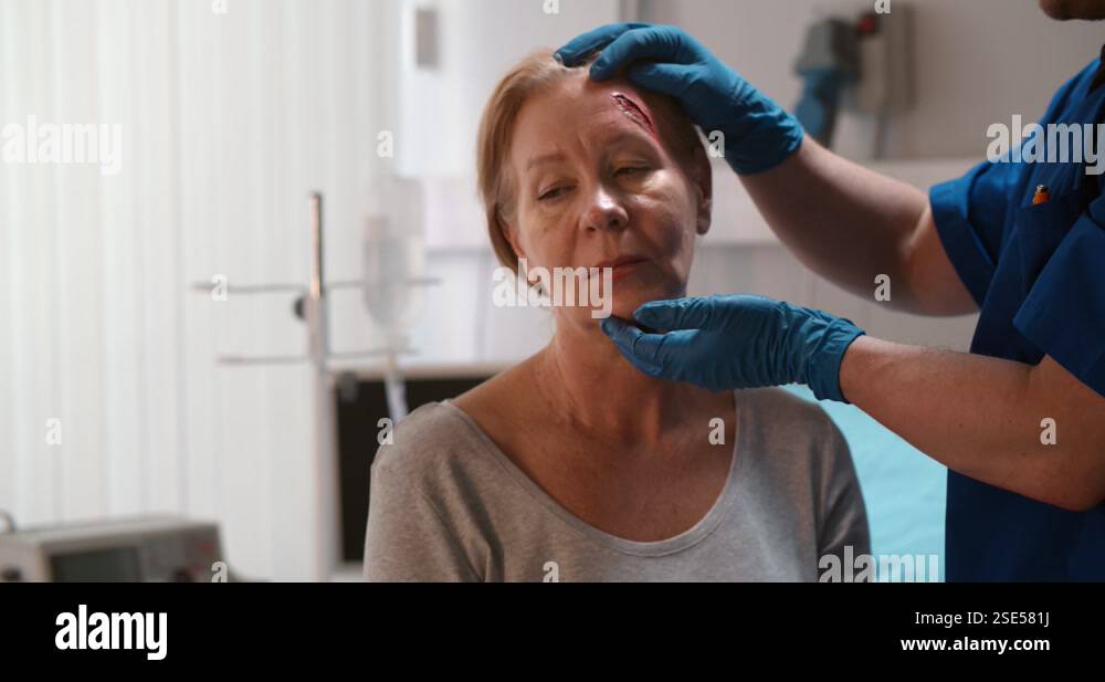 Male doctor examining wound on aged woman forehead in clinic Stock ...